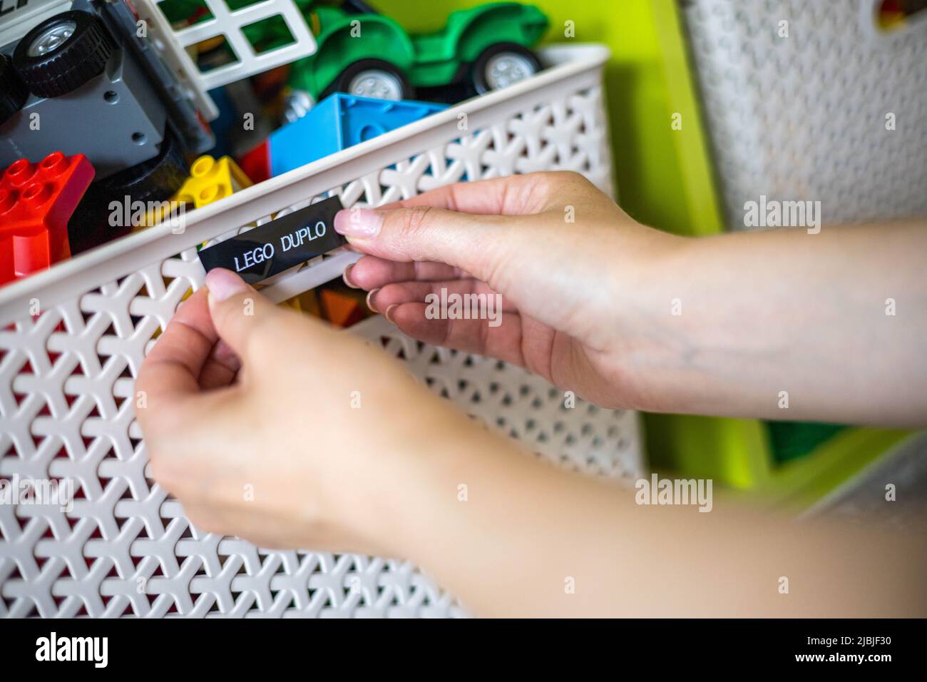Mother hands sticking label sticker with name title of toy for ...