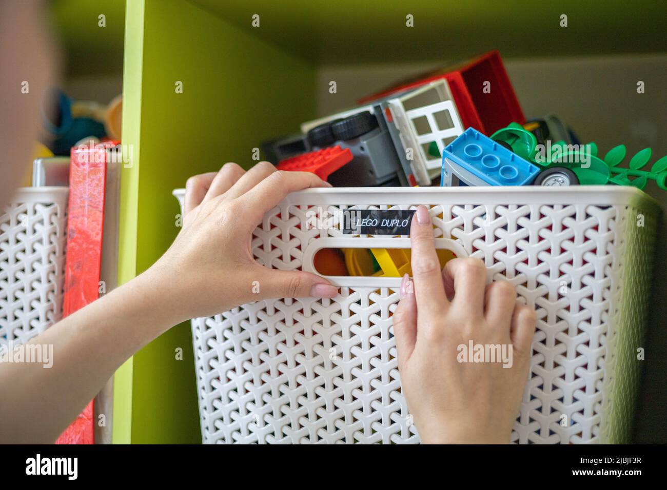 Mother hands sticking label sticker with name title of toy for ...