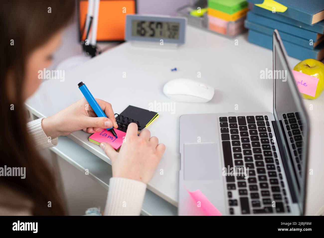 A young girl is scrawling words in English on small pieces of paper ...