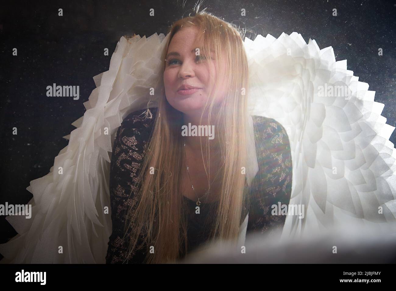Portrait of young woman with long hair, white angel wings and feathers ...