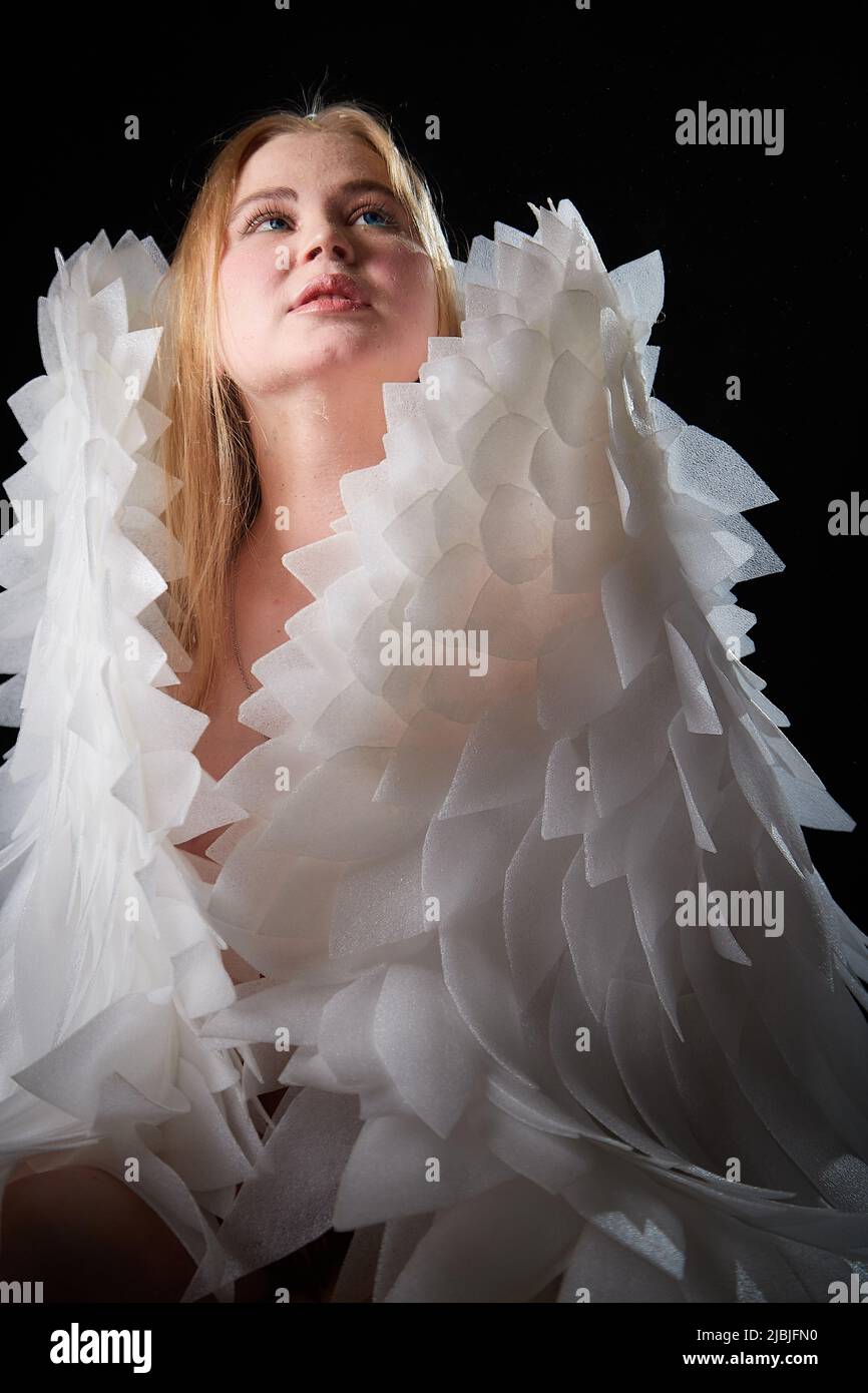 Portrait of young woman with long hair, white angel wings and feathers ...