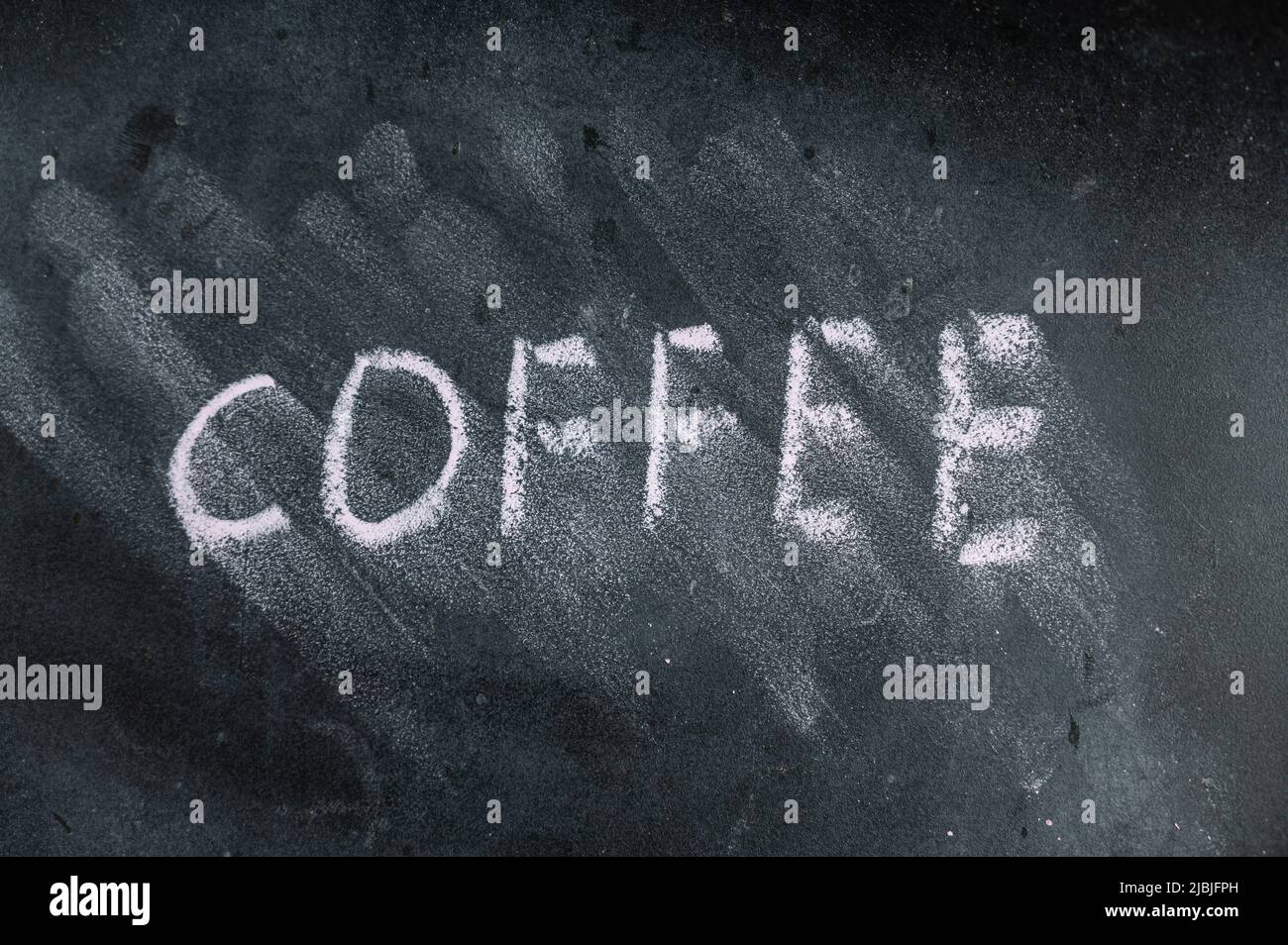 The semi-erased word COFFEE on black chalkboard. Handwritten word ...