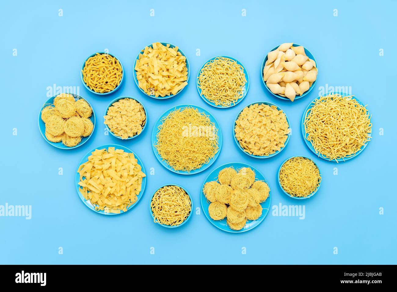 Top view with uncooked pasta of different types on a blue table ...