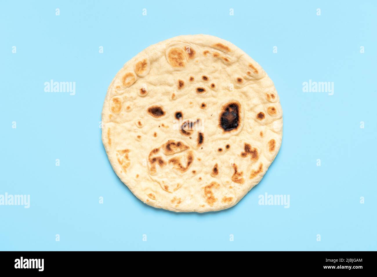 Top view with single naan bread on a blue table. Delicious homemade ...