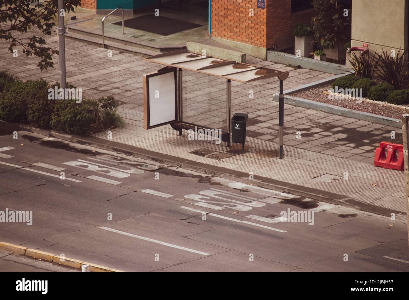 High angle shot of an empty bus stop on a pavement against an asphalt ...