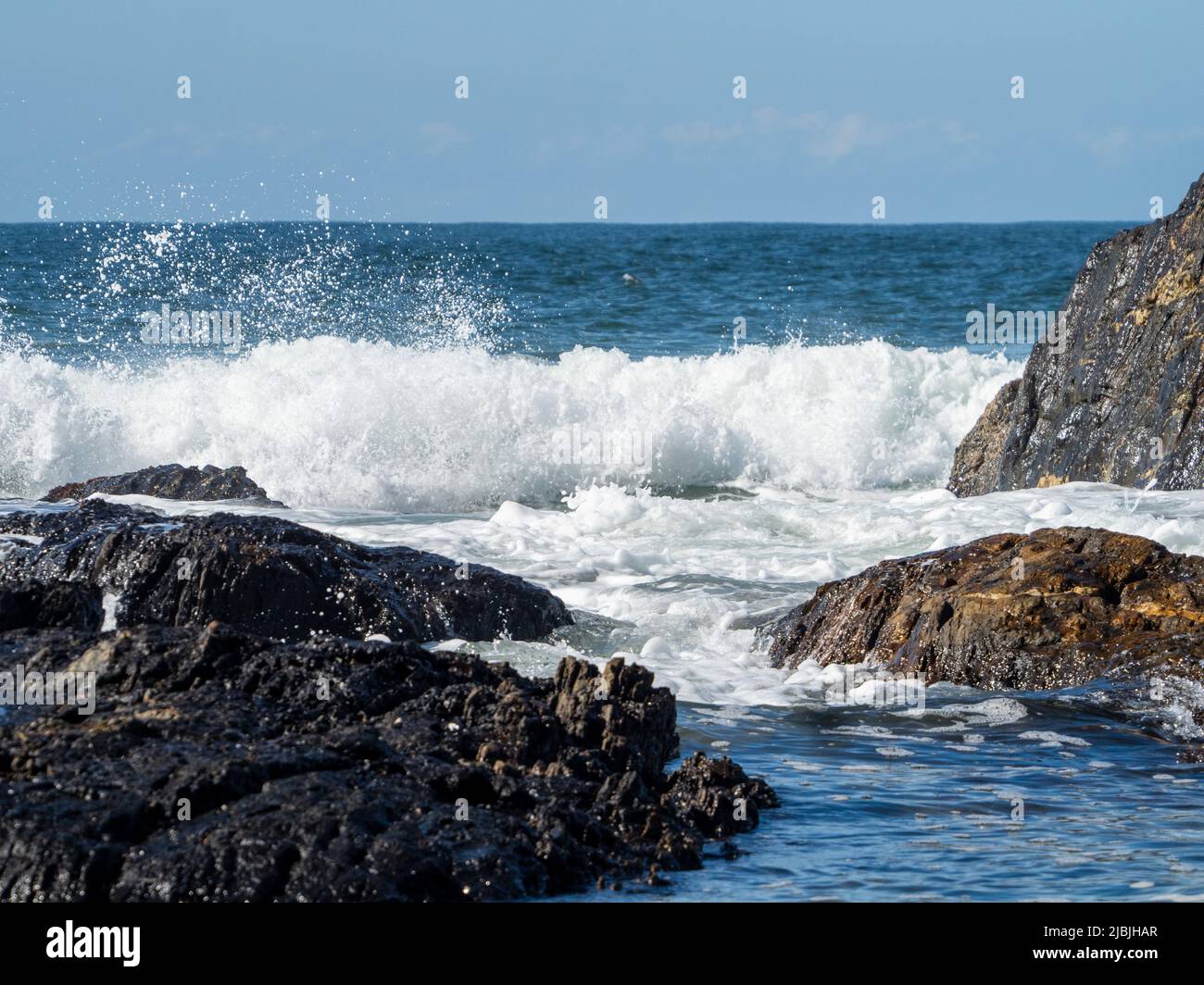 Sea waves crashing in over rocks at the beach, Sea spray flying ...