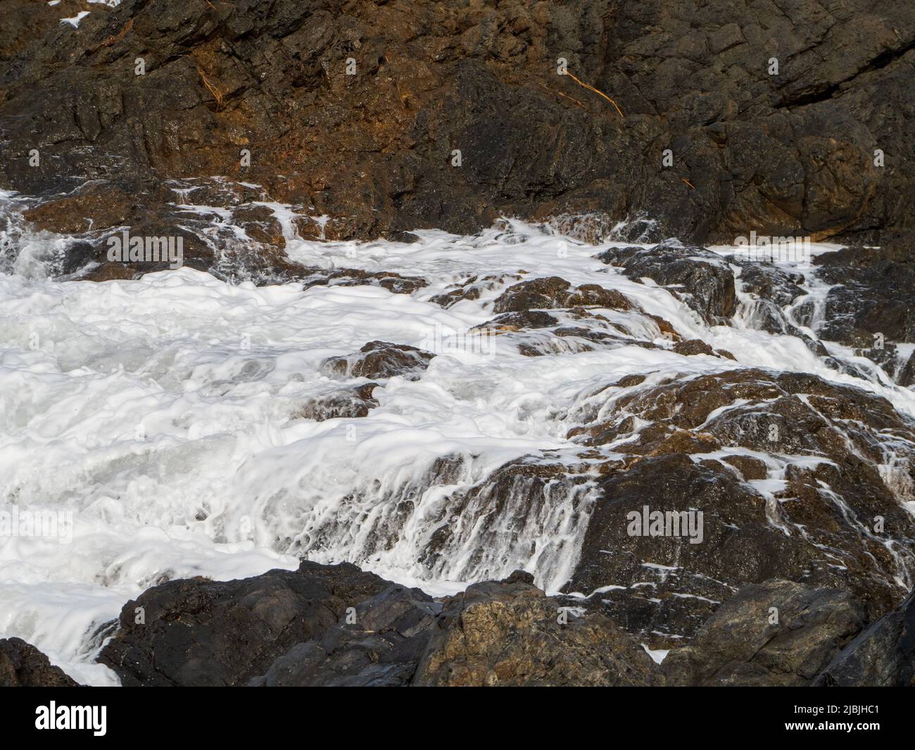 Waves crashing over rocks, sea water cascading down, sea spray flying ...