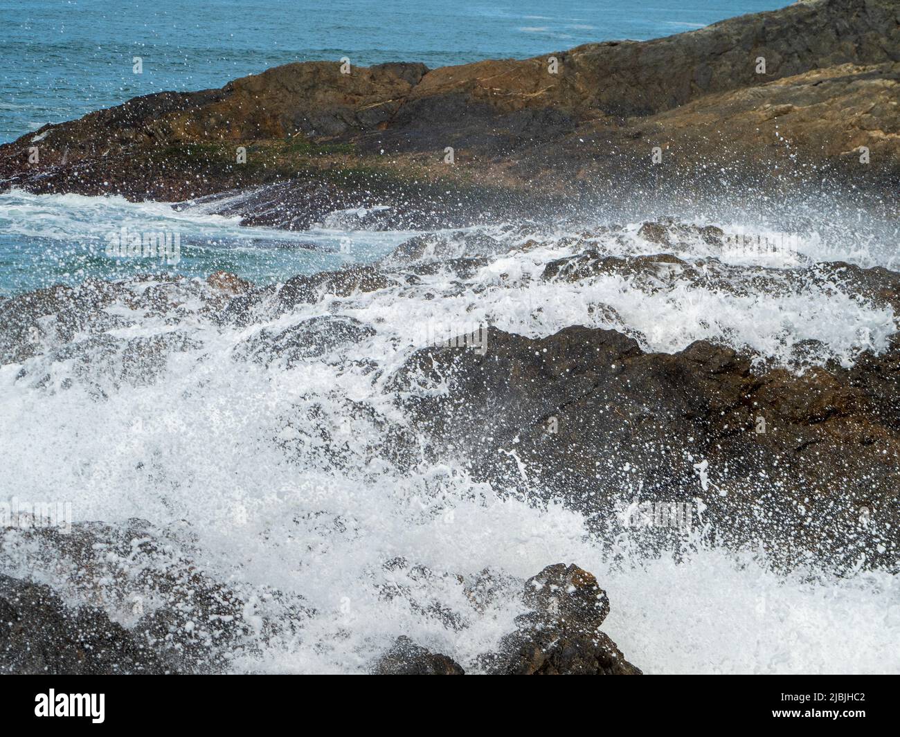 Waves crashing over rocks, sea spray flying, sea water turning white ...