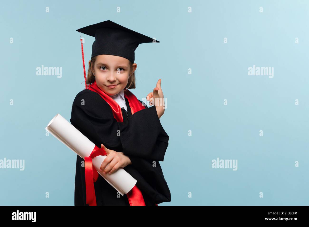 Proud child girl in graduate suit with certificate diploma on light ...