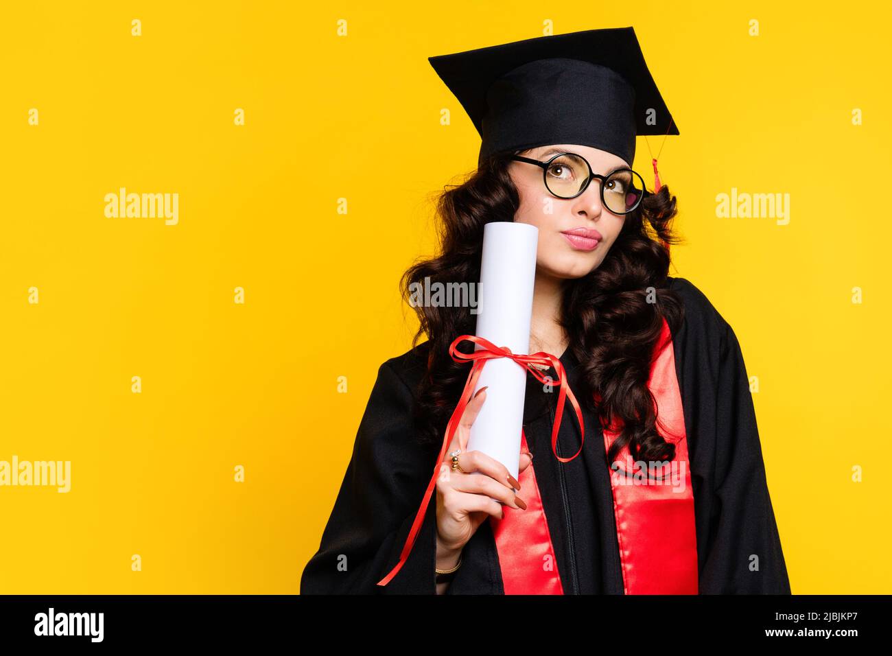 Girl graduate in graduation hat and eyewear with diploma on yellow ...