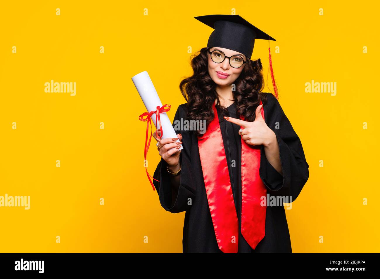Girl graduate in graduation hat and eyewear with diploma on yellow ...