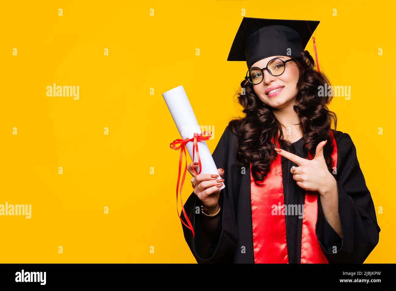 Girl graduate in graduation hat and eyewear with diploma on yellow ...