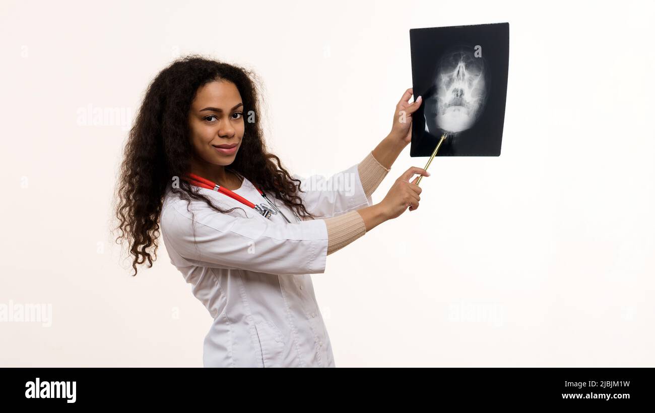 Dark-Skinned Female doctor examining an x-ray scan on light background ...