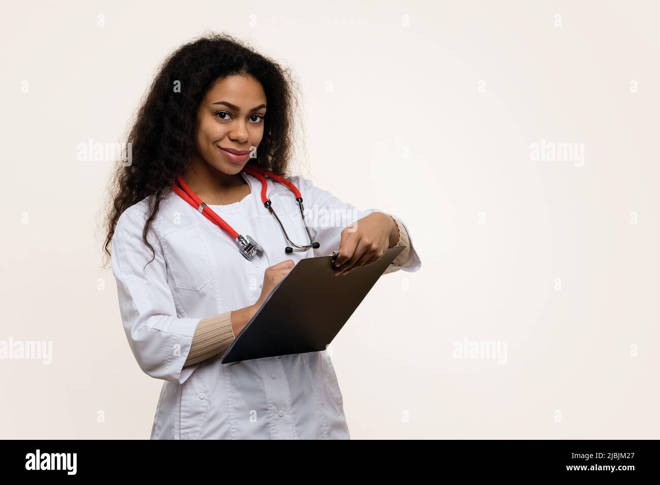 Friendly Dark Skinned Female Doctor in Uniform with Stethoscope filling ...