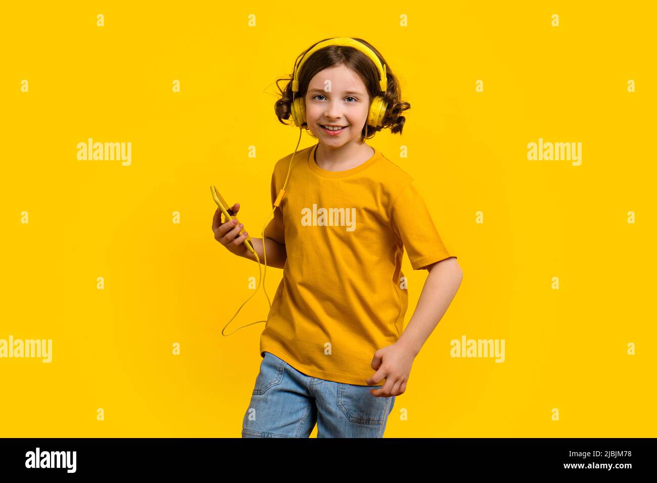 Cheerful short curly hairdo school girl dance to favorite song moves to ...