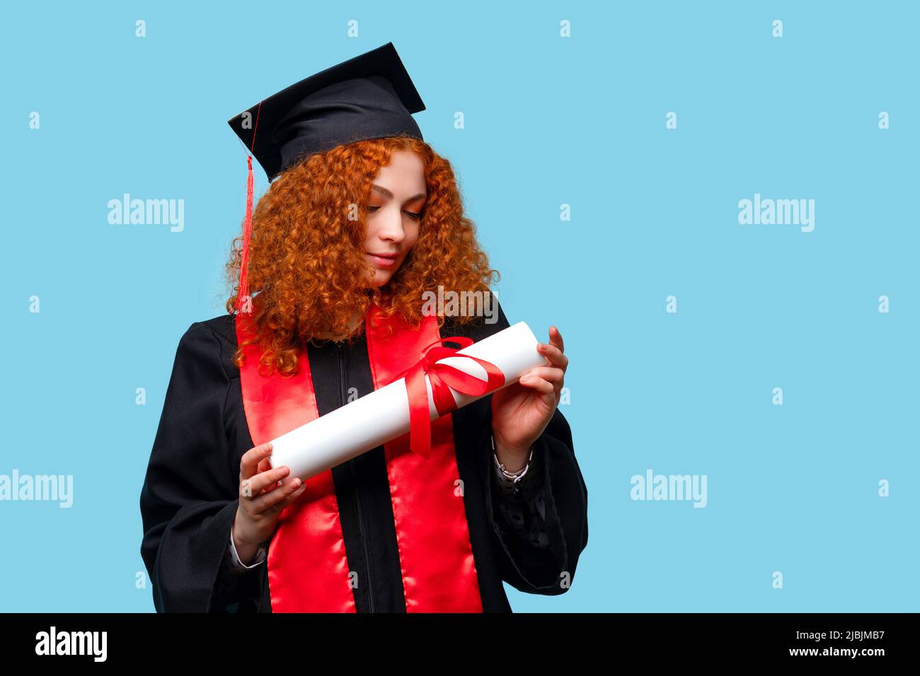 Shy Curly Red Haired Female Graduate in Ceremony Robe and Graduation ...