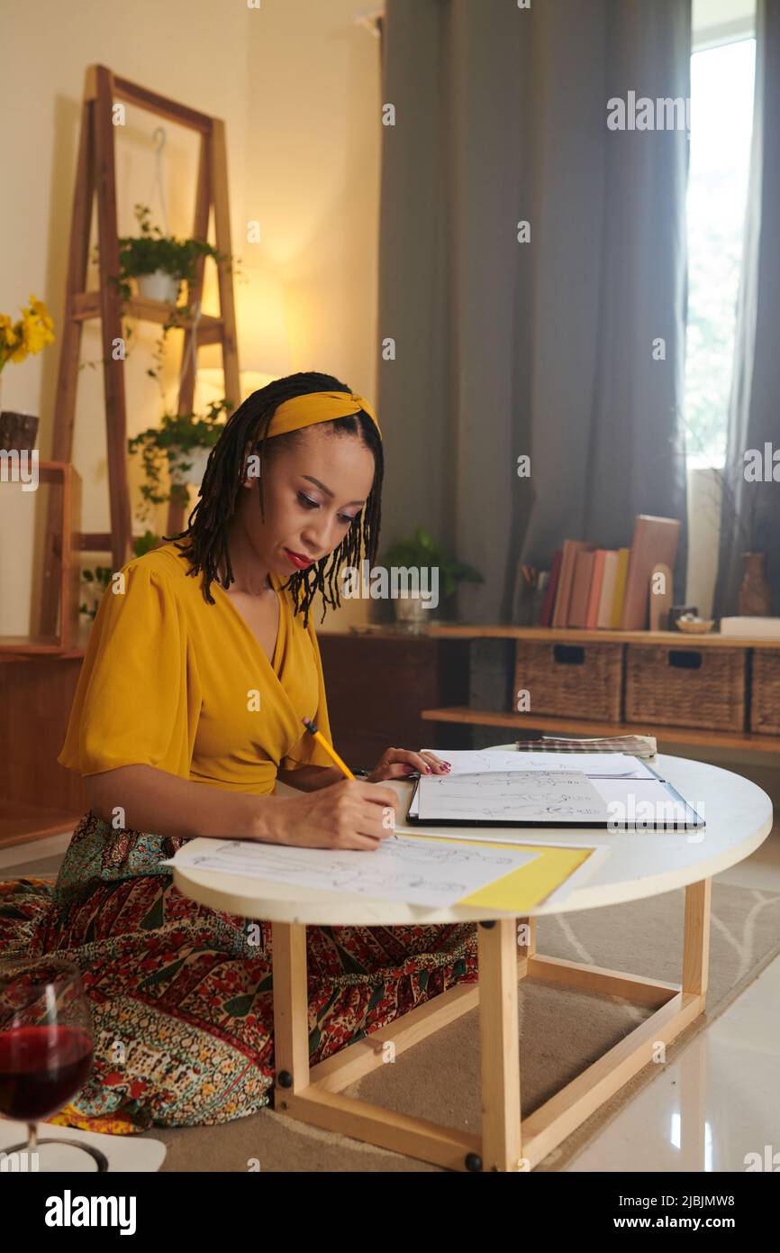 Creative Black woman drawing fashion sketches for new collection of ...