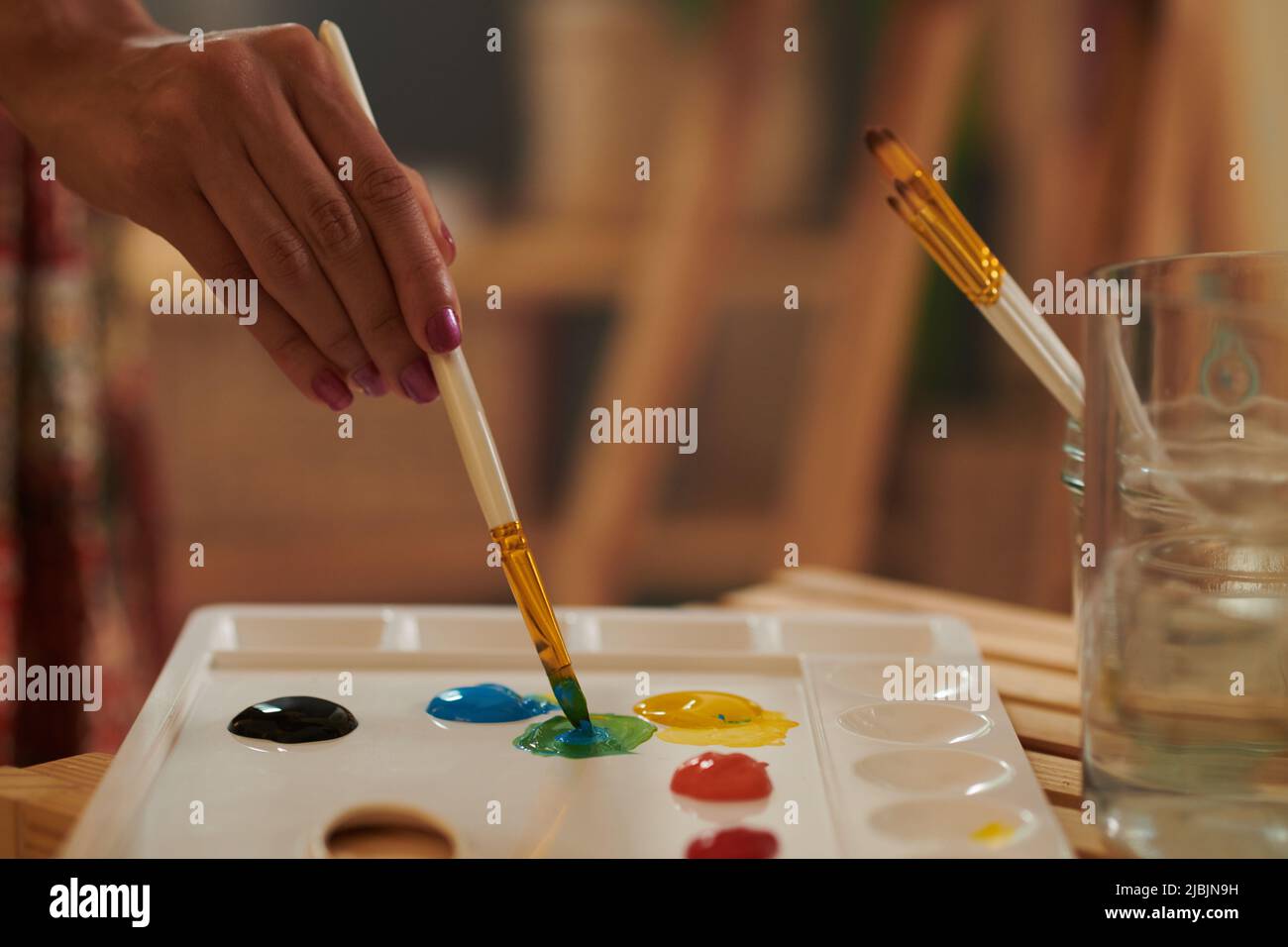 Hand of female artist mixing green and blue colors on palette Stock ...