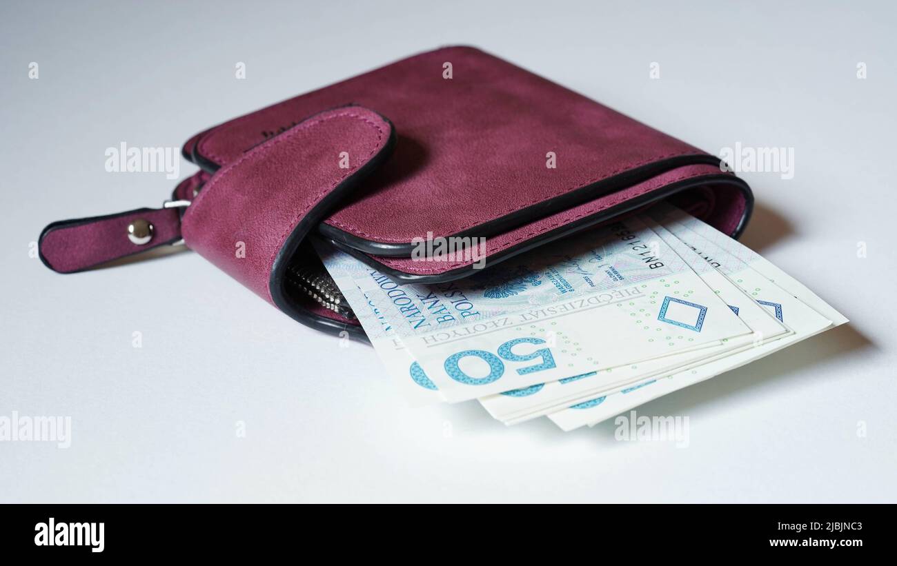 Close-up of a purple wallet, zloty banknotes on a white background ...