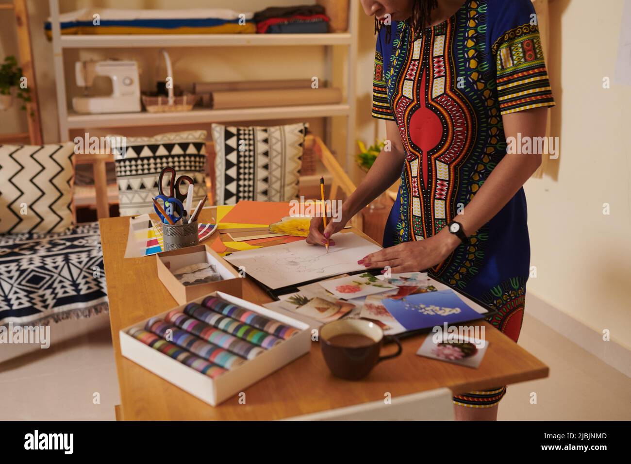 Black woman drawing pattern for fabric to incorporate in her fashion ...
