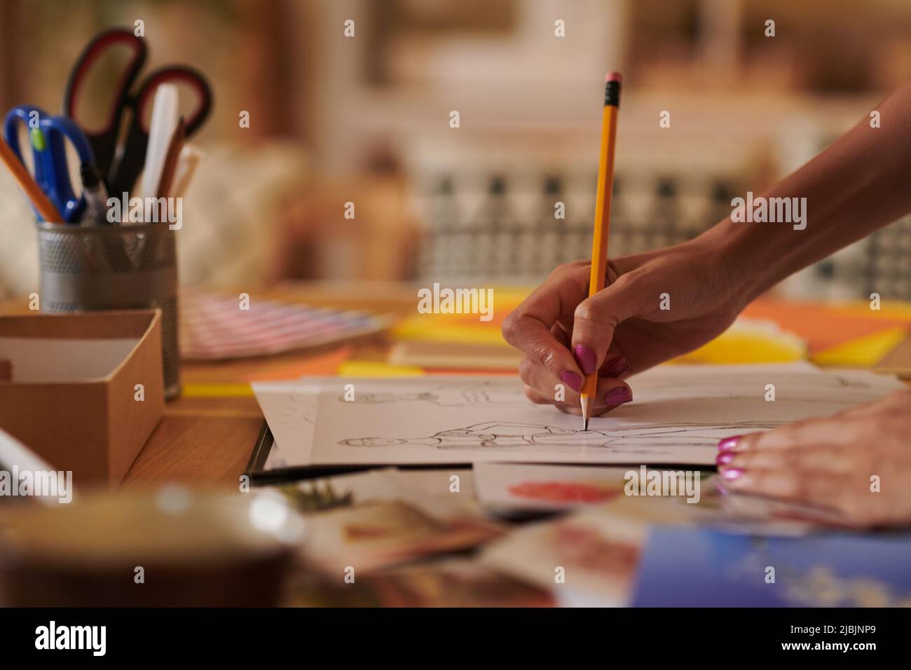 Close-up image of fashion designer drawing sketch at her desk in studio ... Close-up image of fashion designer drawing sketch at her desk in studio ...