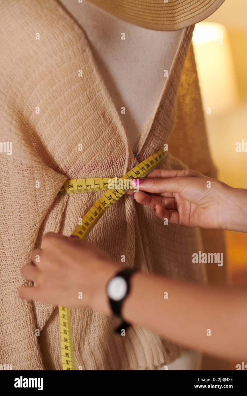 Close-up image of tailor checking measurement of knitted sweater on ...