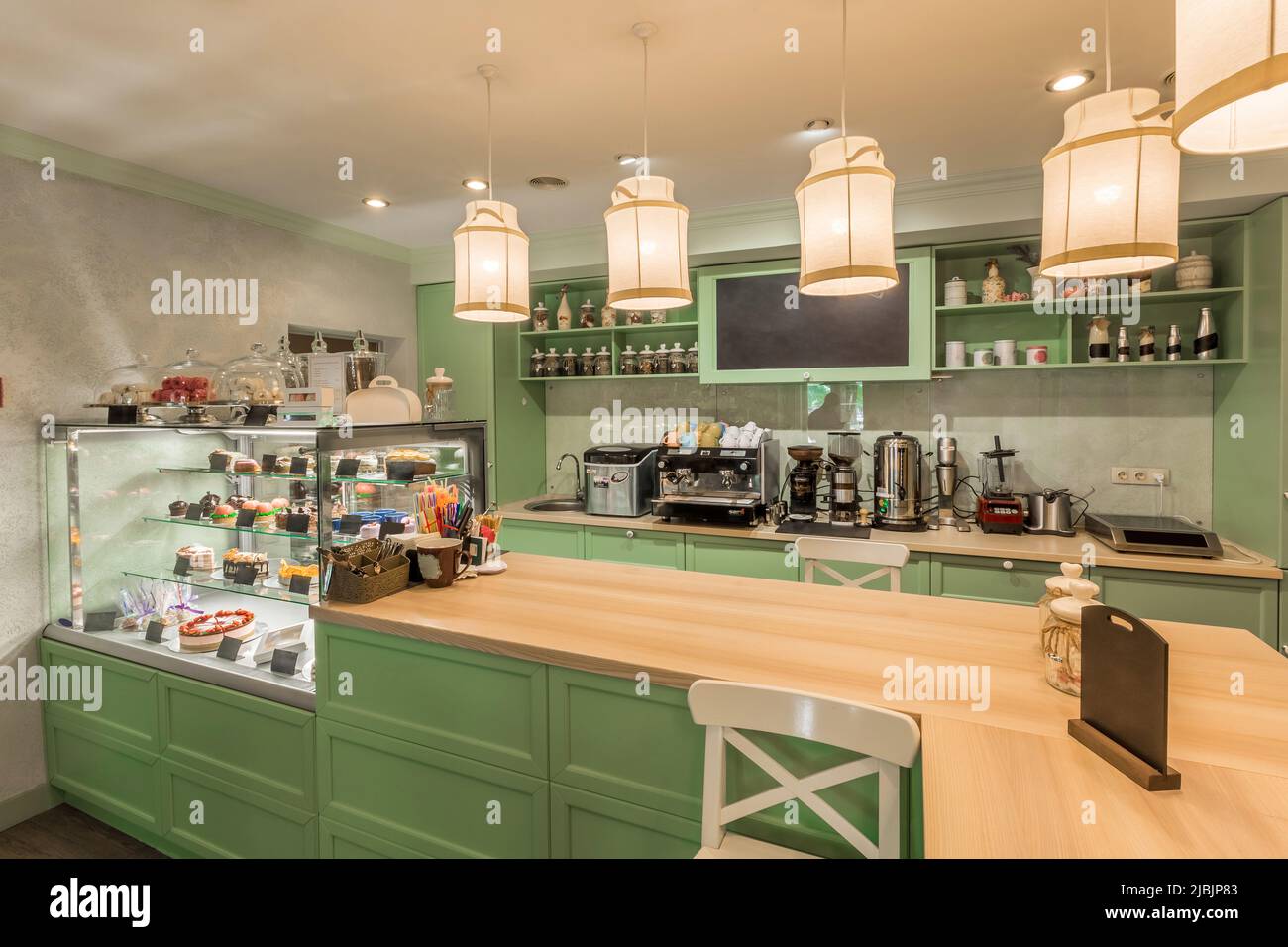 Cozy cafe interior with pastel green counter and glass display with ...