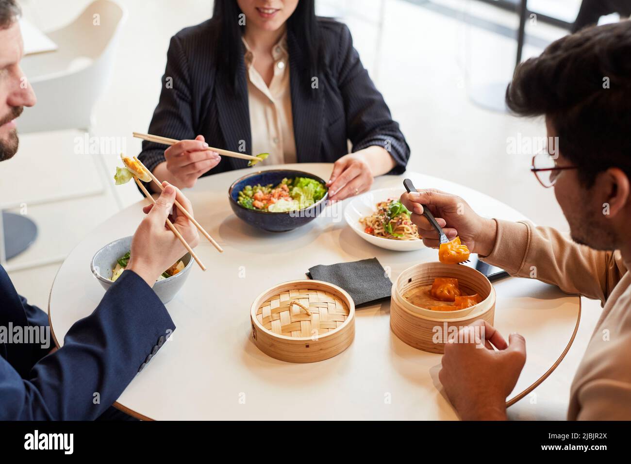 High angle close up of four people enjoying Asian food at round table ...