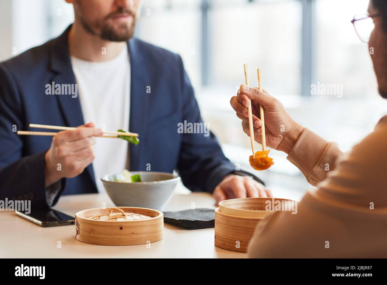 Closeup of businessman enjoying Asian food during business lunch with ...