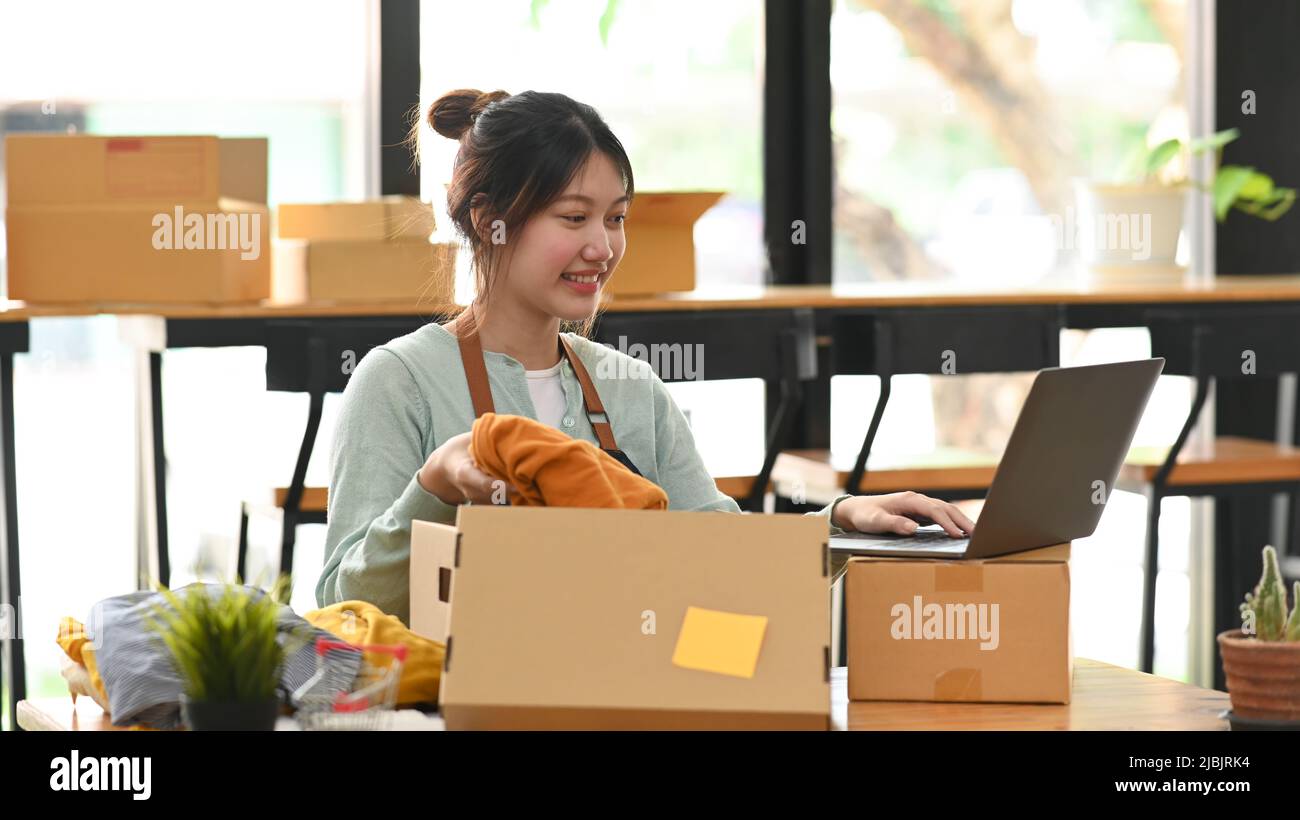 Young asian woman online seller working with laptop and preparing ...