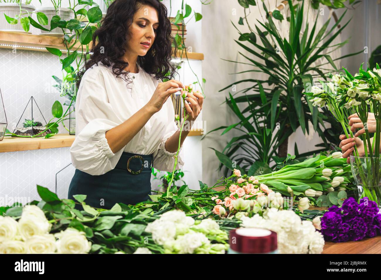 Attractive young woman florist is working in a flower shop Stock Photo ...