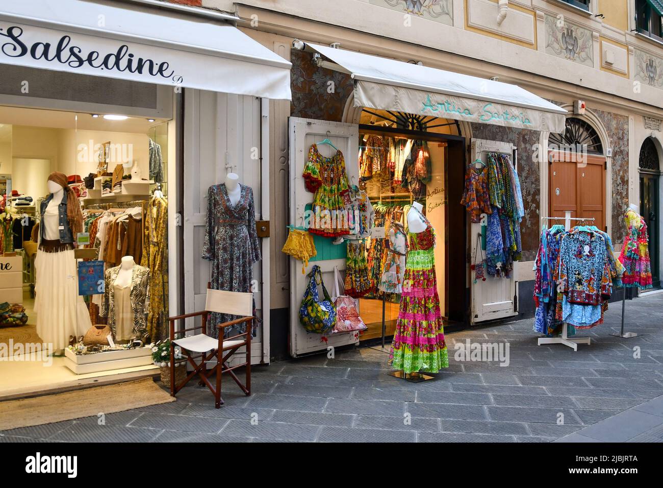 Exterior of fashion shops with clothes displayed on the sidewalk in the ...