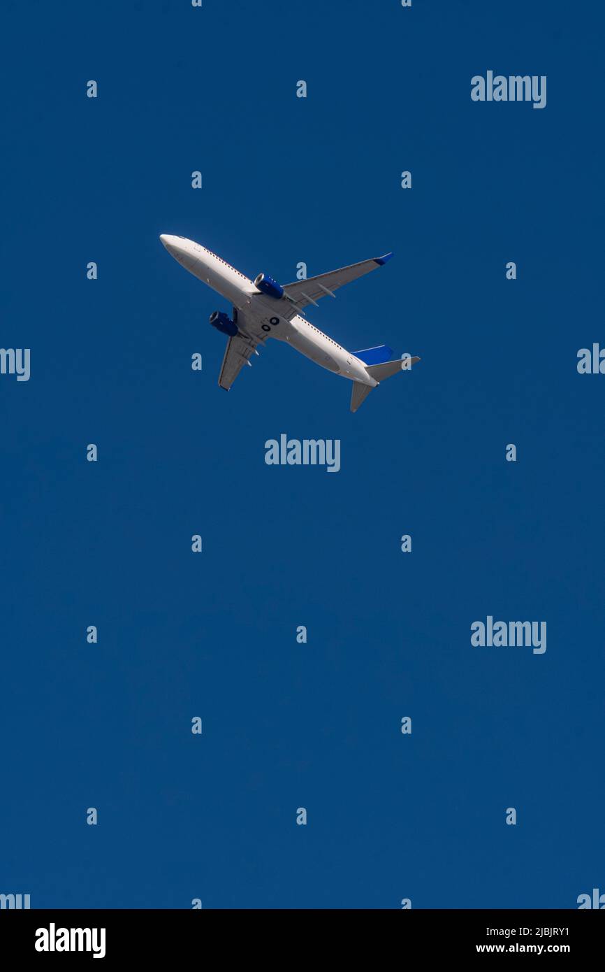 Aerial view of white airplane with blue tail, shot from below with ...