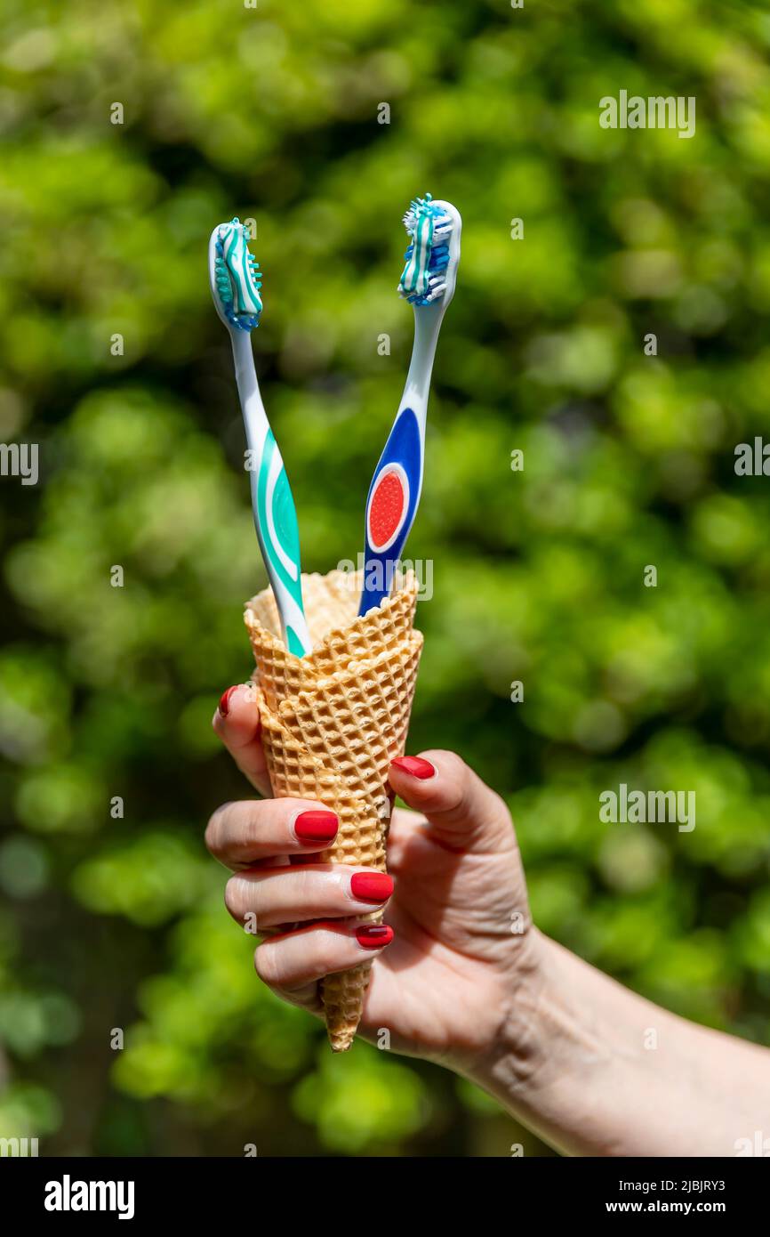 Two toothbrushes with toothpaste are placed inside a cone, like those ...