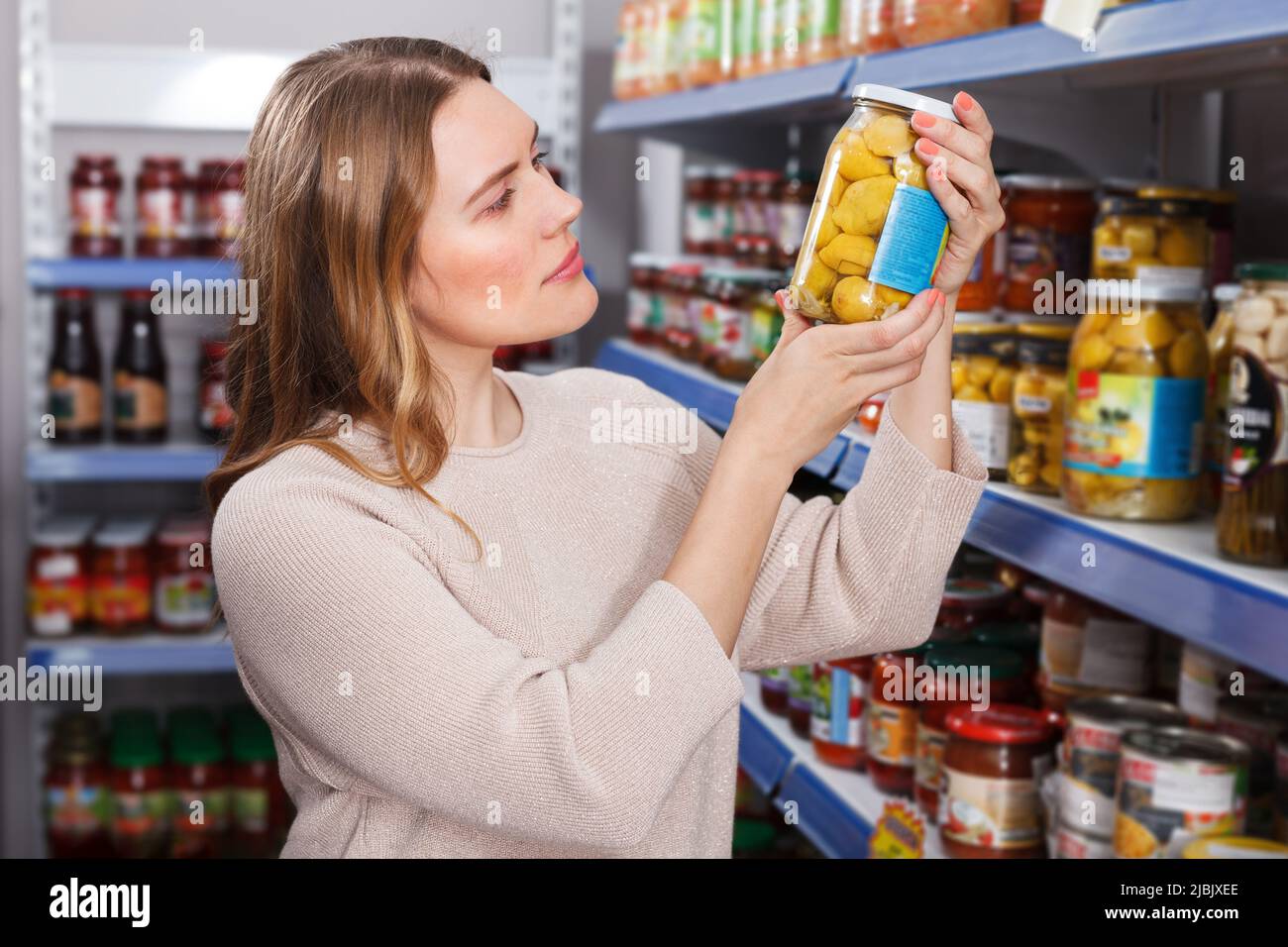 Serious female in the shop selection pickle goods indoor Stock Photo ...