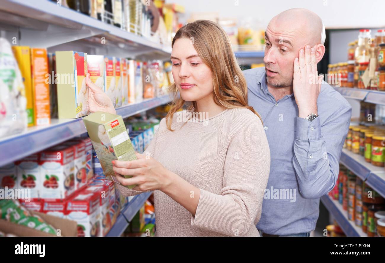Woman and worried man choosing groats in grocery food shop Stock Photo ...