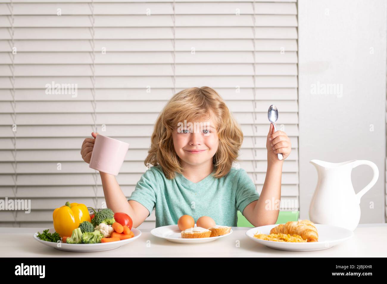 Schoolchild eating breakfast before school. Portrait of little teen ...