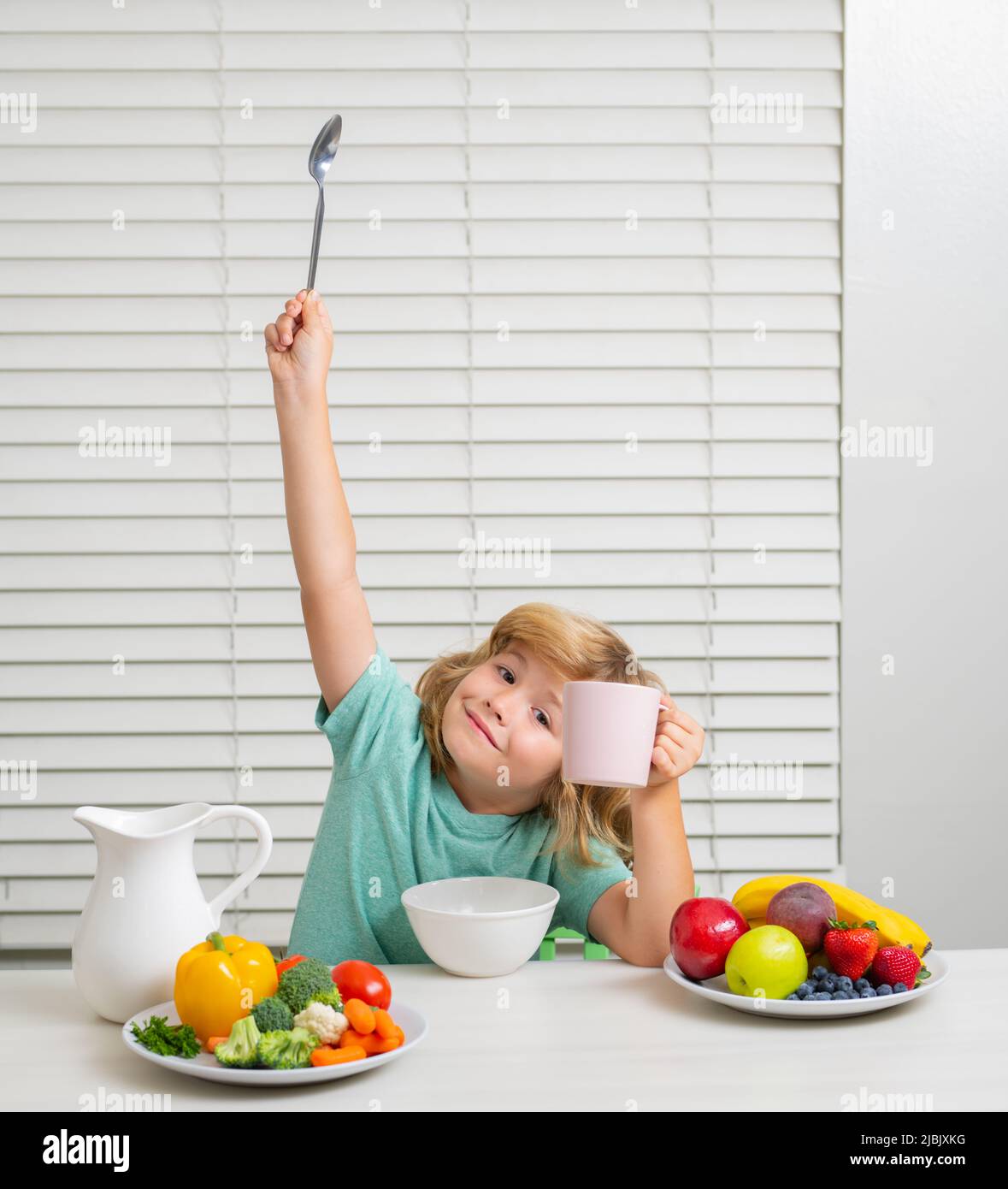 Kid boy eating healthy food vegetables. Breakfast with milk, fruits and ...