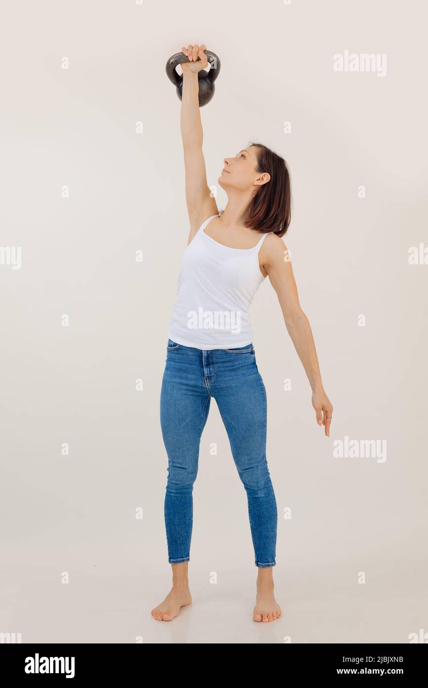 Young athletic woman lifting up kettlebell and putting down arm, white ...