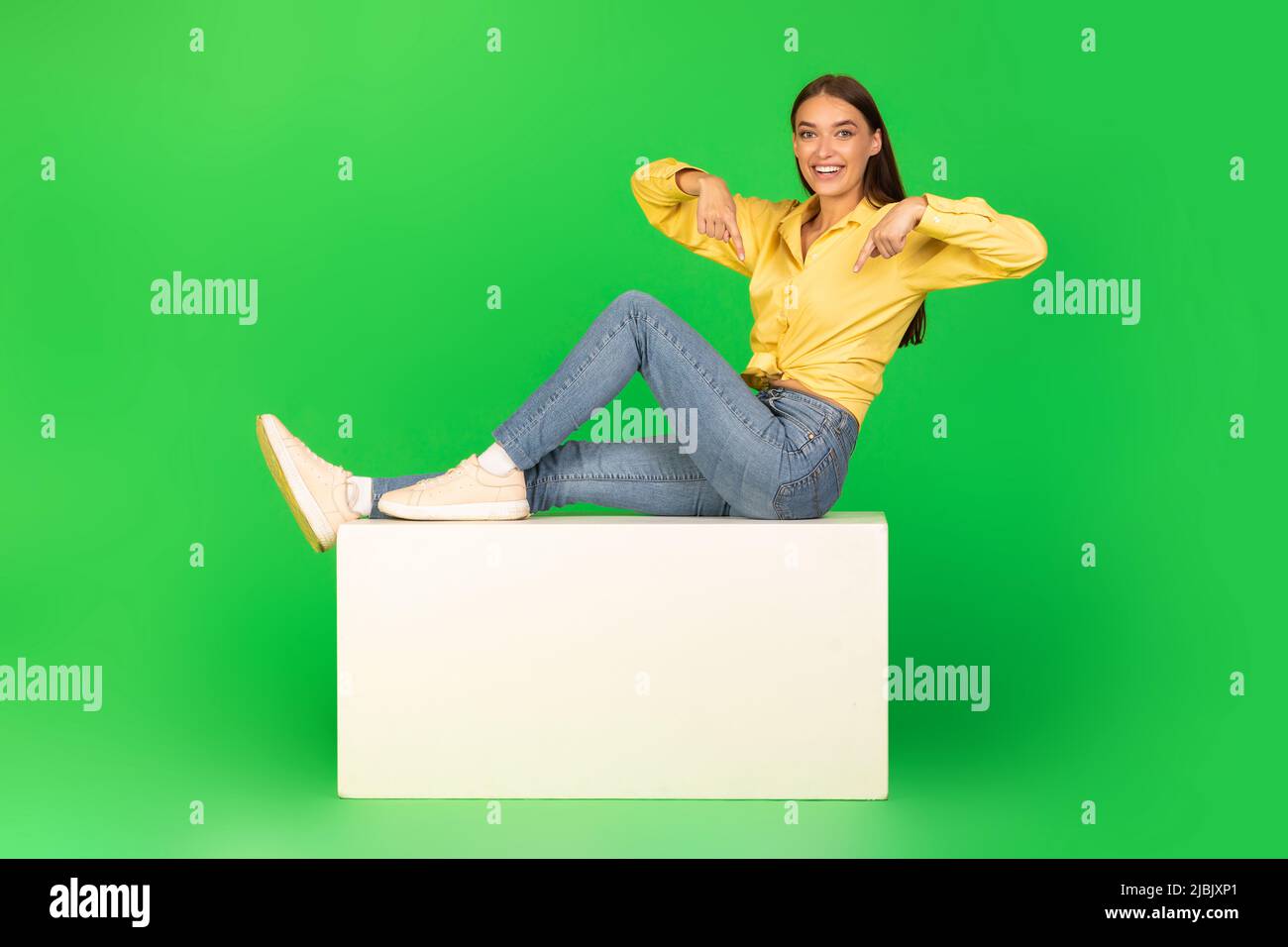 Happy Female Pointing Fingers At Stand Sitting Over Green Background ...