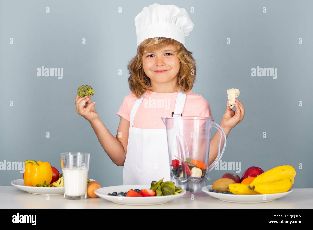 Child chef cook hold broccoli prepares food on isolated grey studio ...