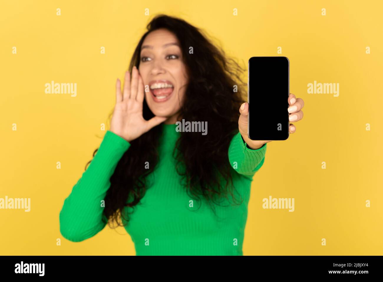 Excited Arabic Woman Showing Smartphone Screen Shouting Over Yellow ...