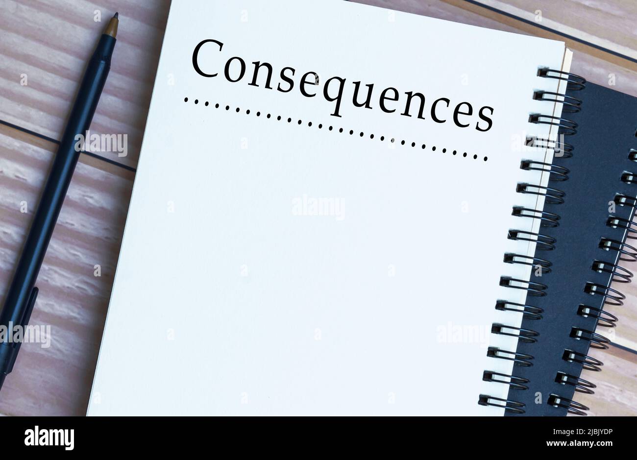 Consequences word written on notepad on wooden desk. Negative, positive ...