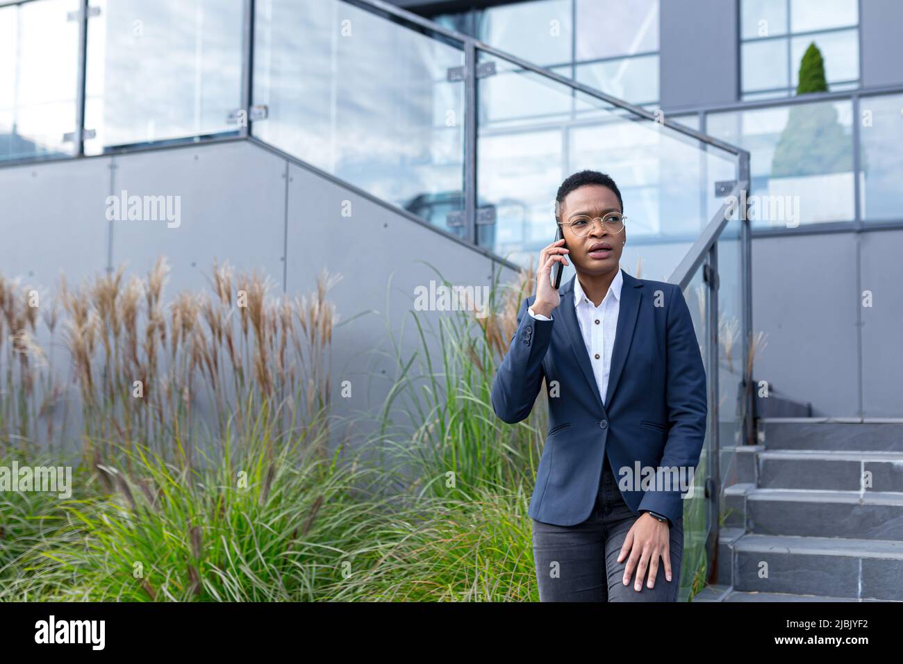 Angry and serious businesswoman talking on the phone outside the office ...