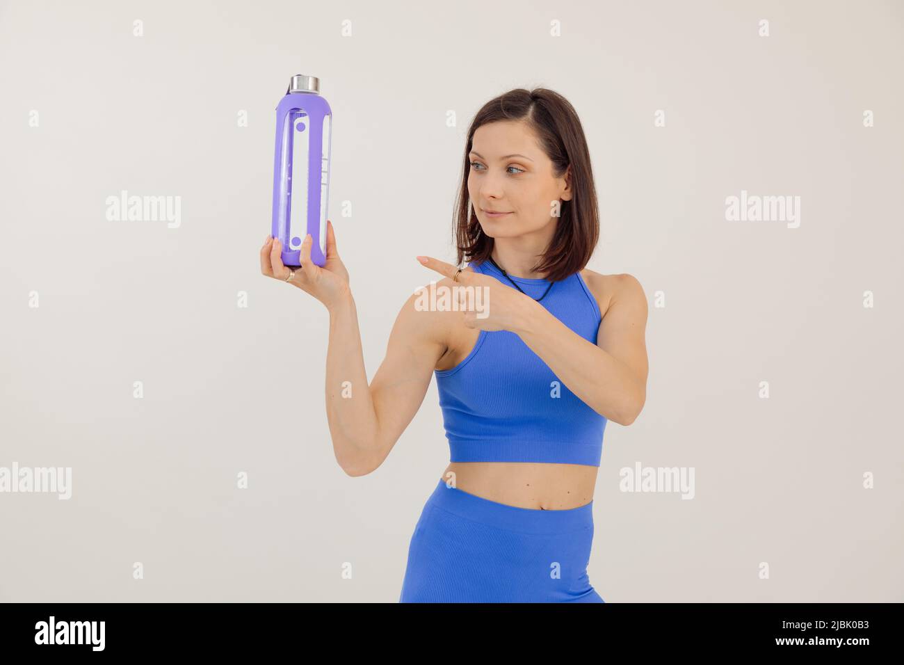 Young athletic woman in blue fitness suit holding and pointing at ...