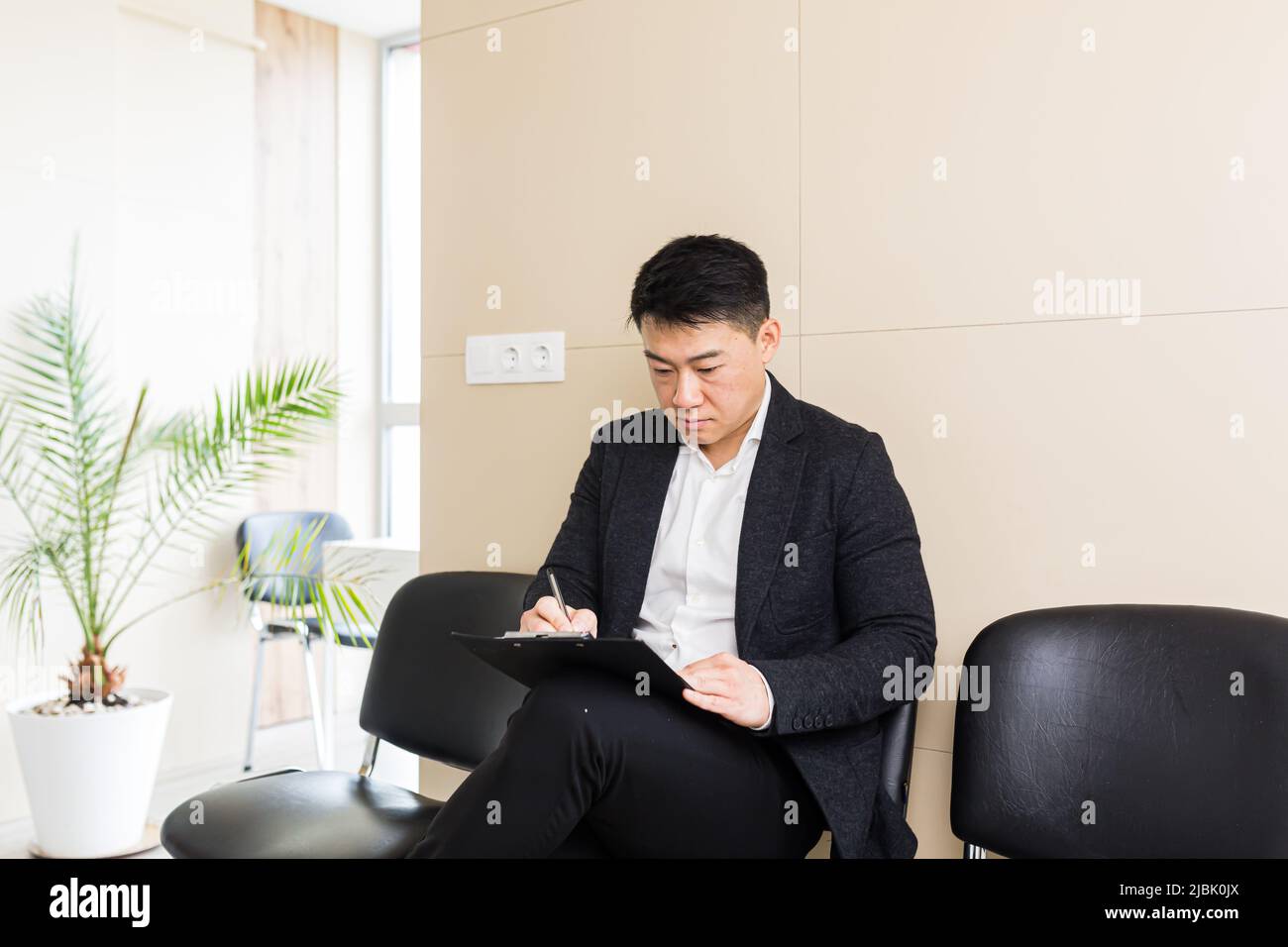 Asian businessman man, in the waiting room sitting on a chair near the ...