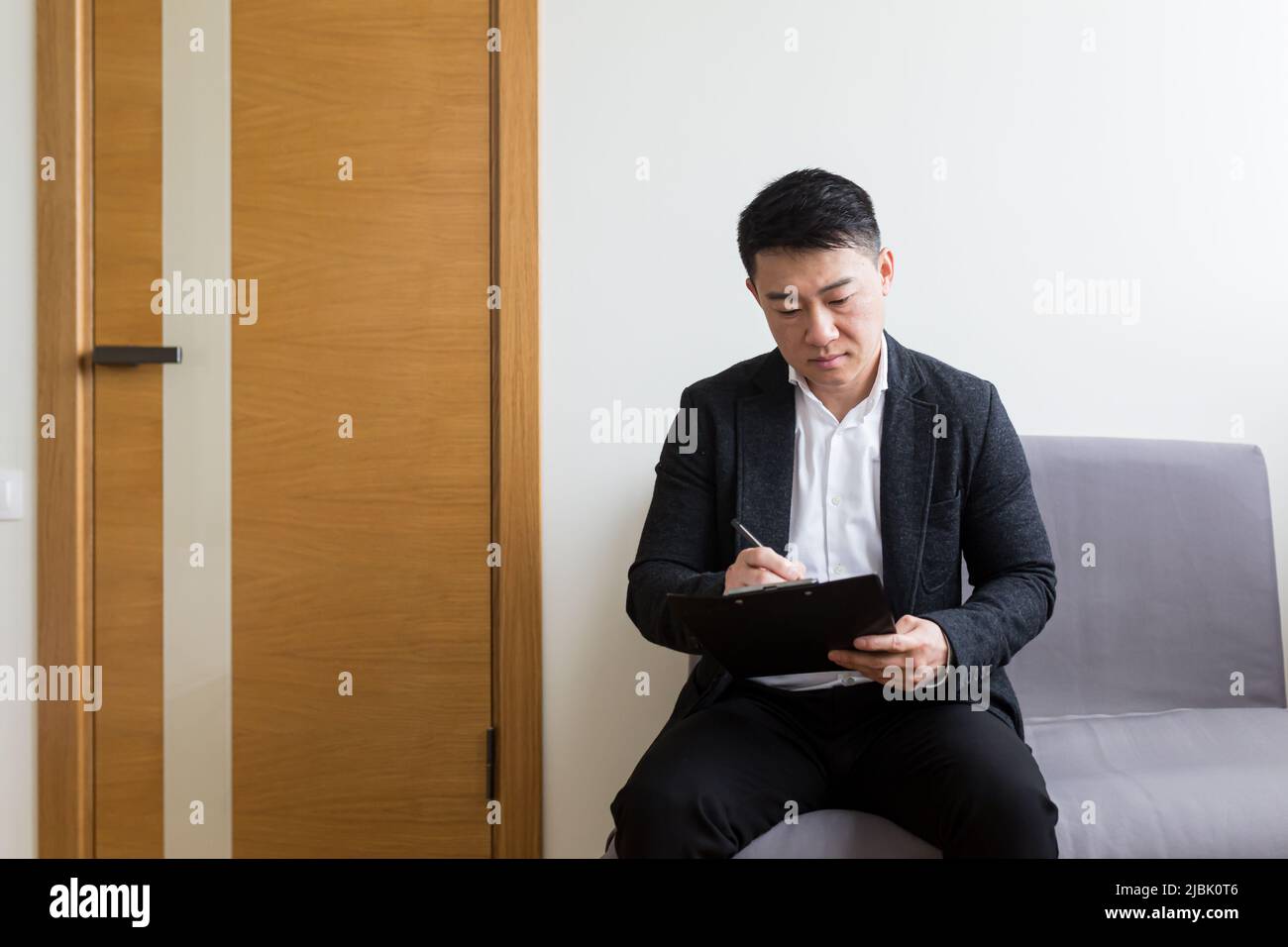 Young successful Asian man, waiting for a job interview, in the waiting ...