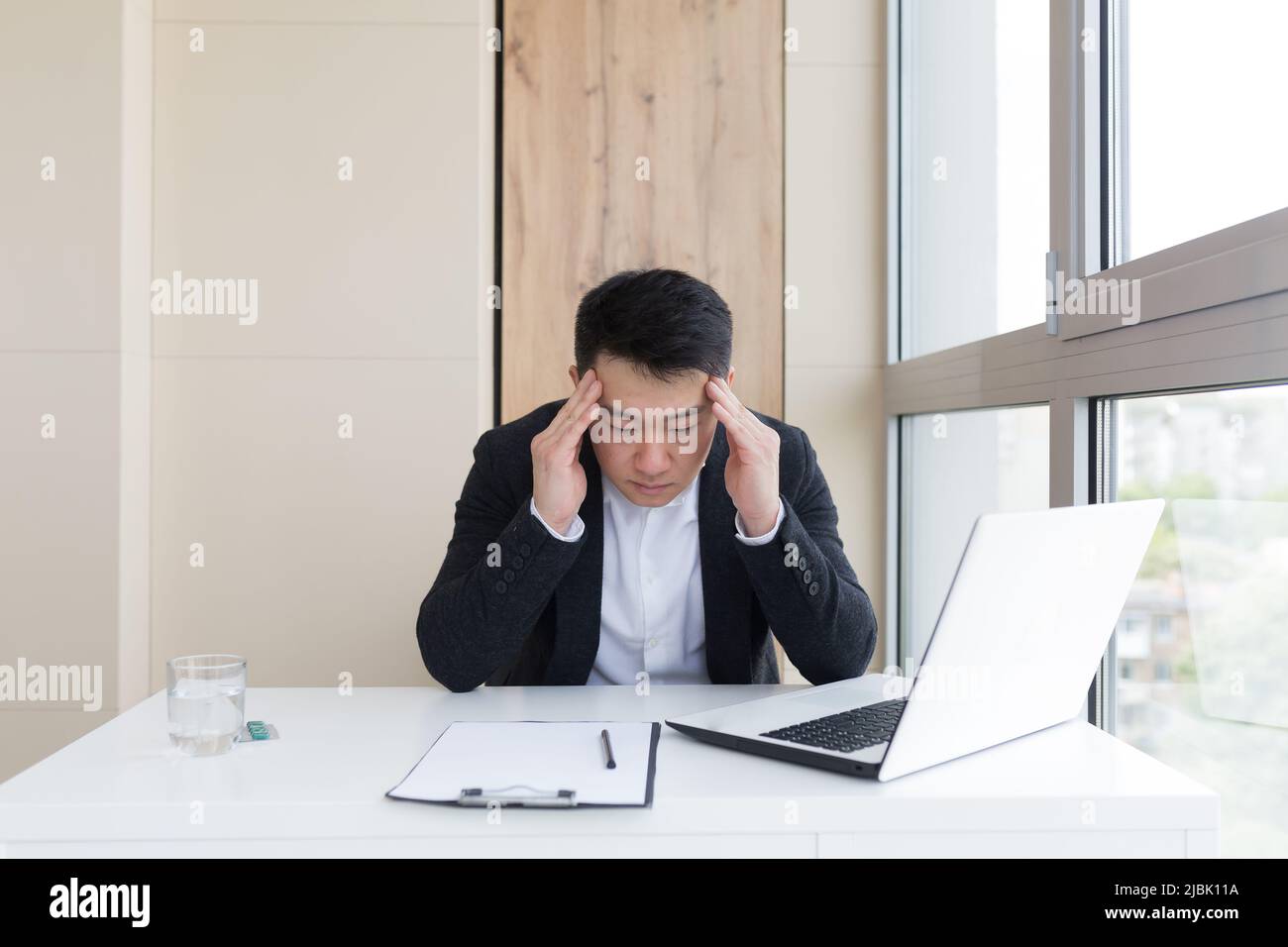 young asian office worker suffering from headache at work in the office ...