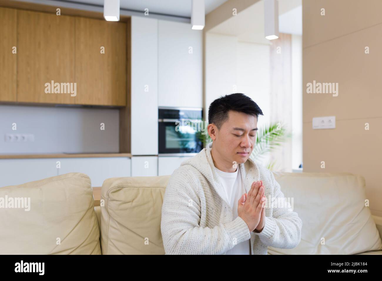 young asian man praying at home alone. Male folding pencil arms and ...