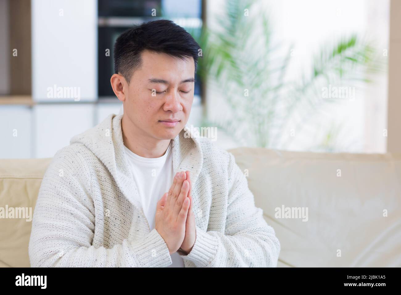 young asian man praying at home alone. Male folding pencil arms and ...